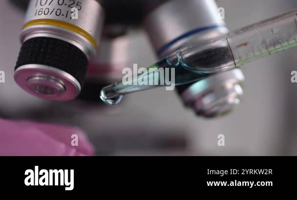 Lab technician pours liquid onto micro specimen for examination ...