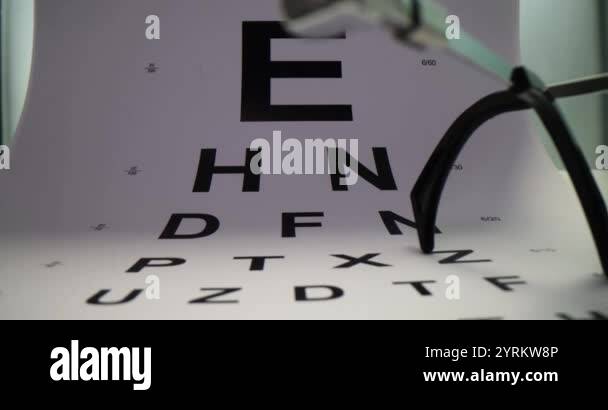 Glasses for checking eyesight neatly placed on table. Snellen chart ...