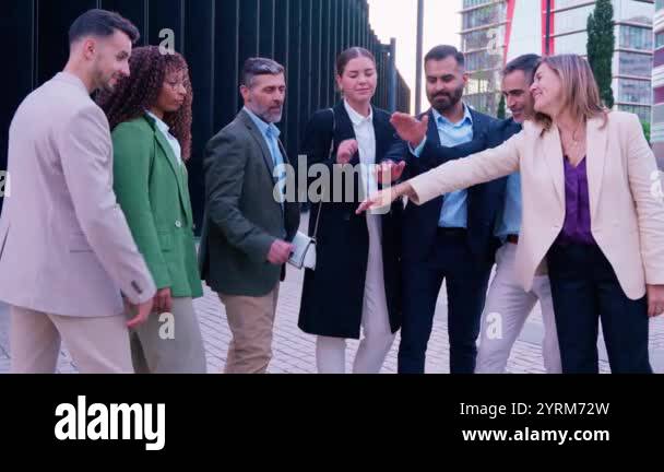 A group of six people standing together outdoors, joining hands in ...
