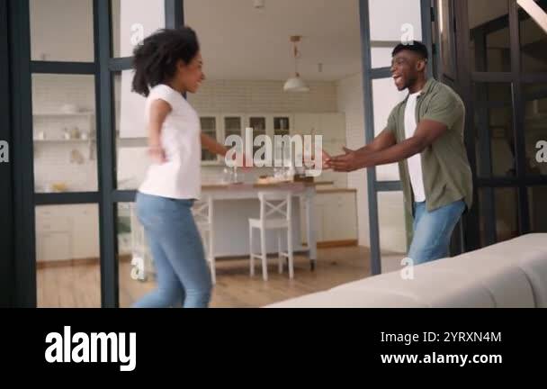 African American love couple happy family meeting at home woman jumping man hugging spinning ...