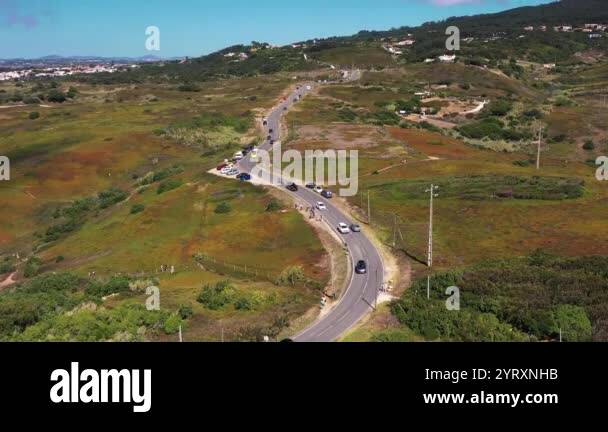 Drone view of a winding two-lane road with moving cars and parked ...