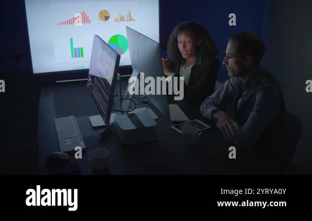 Professionals analyzing and interpreting data visualizations on multiple screens in a modern ...