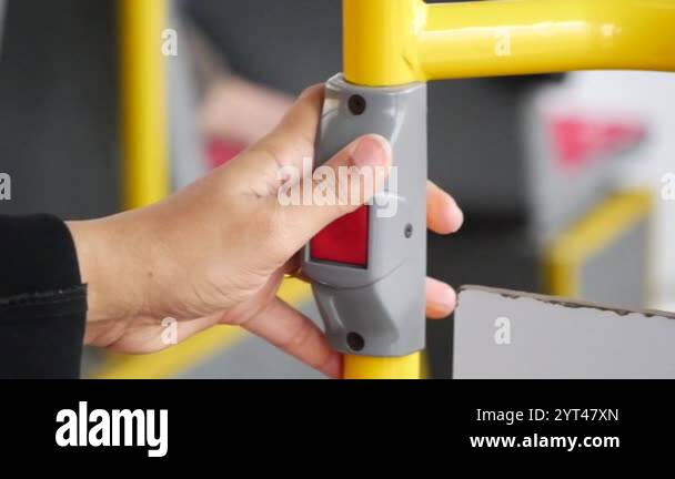 A hand is pressing a bus stop request button located in public ...