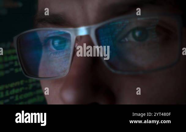 Close-up portrait of focused software engineer wearing eyeglasses looking at computer screen ...