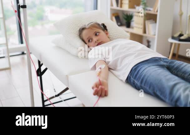 Young Caucasian girl lying on medical couch during blood transfusion ...