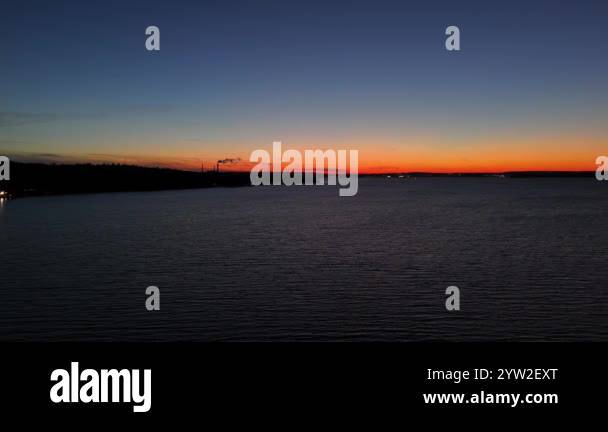 Sideways flight to the left over a lake with dark forested shore and ...