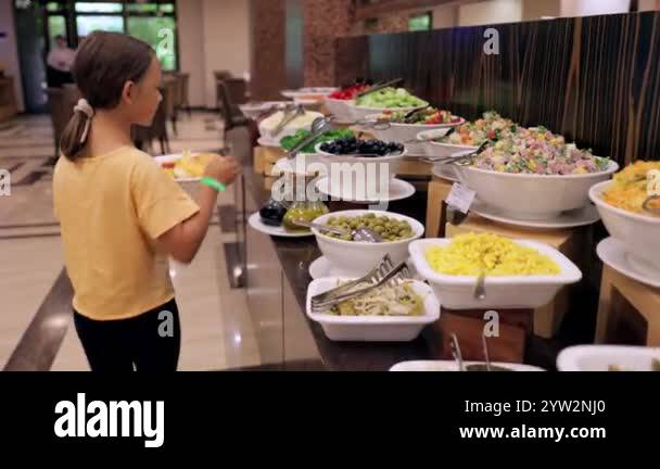 A girl selects her food at a hotel breakfast food court, adding ...