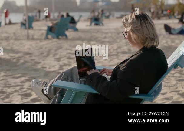 A peaceful beach scene featuring a person working on a laptop, happily ...