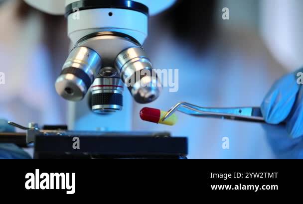 Pharmacist scientist with capsule with medicine under microscope to ...