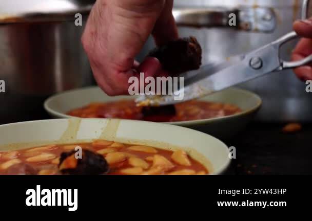 unrecognizable cook cuts with his scissors chunks of black pudding to ...