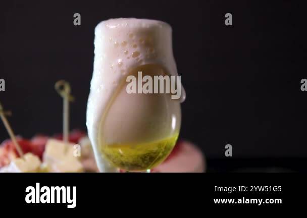 Beer in a beer glass, forming effervescent bubbles and a frothy head ...