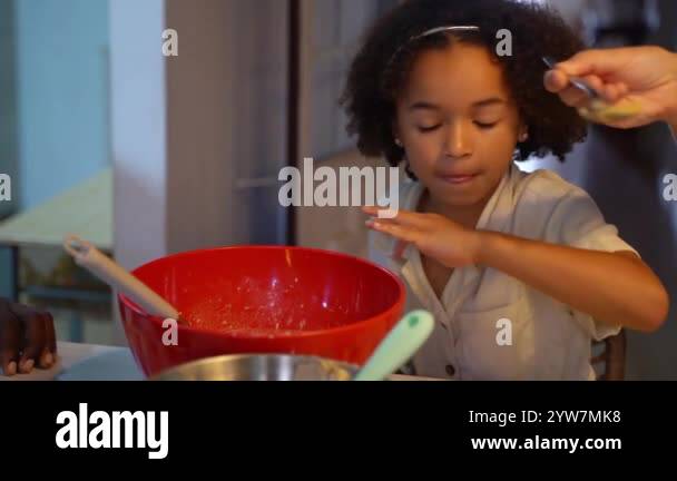 Black skin child cooking pancakes, mixes dough in a bowl with a spoon ...