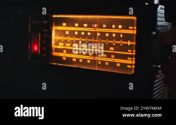 Extreme close-up of a hand turning a tuning knob on a vintage radio ...