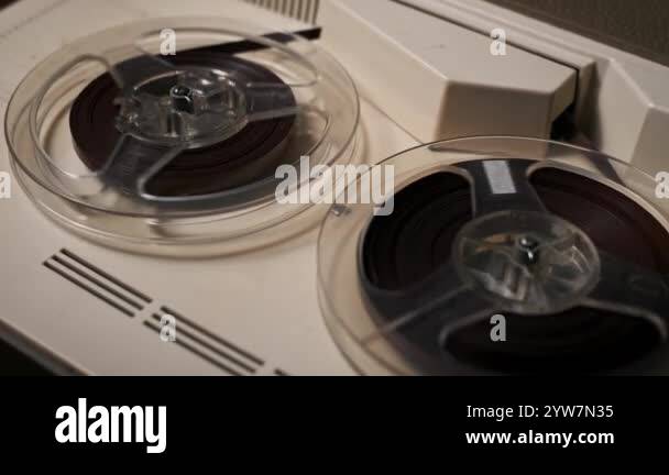 A detailed close-up of a dual reel-to-reel tape recorder with spinning ...