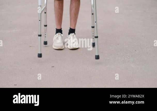 A close-up of a young mans legs and walker on a park path, highlighting ...