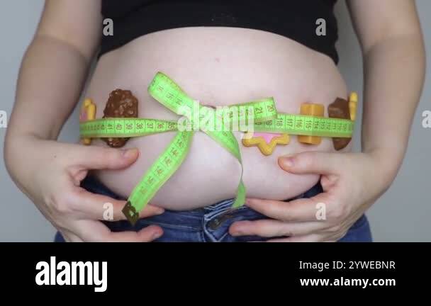 Obesity and overweight from overeating. Big belly tied with measuring ...