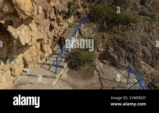 A woman descends the stone steps toward the edge of a cliff, heading to ...