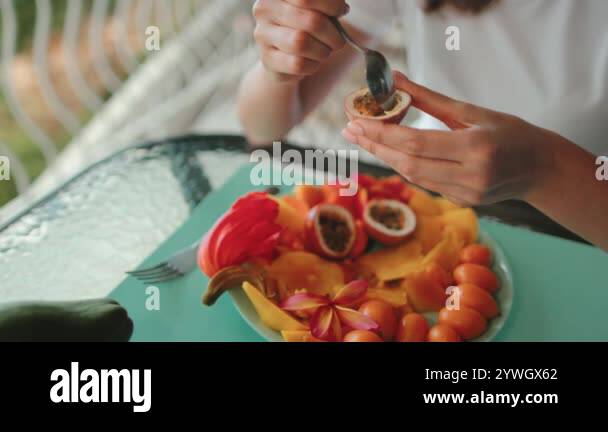Indulging in scooping out passion fruit pulp, a woman enjoys a plate of ...