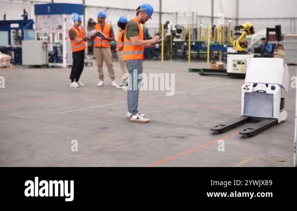 Multiracial team of industrial engineers testing an automated guided ...