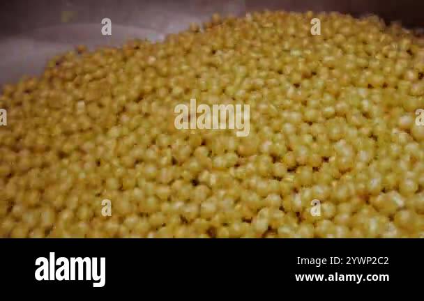 Close-up of yellow caramel round candies rotating in a drum at a ...