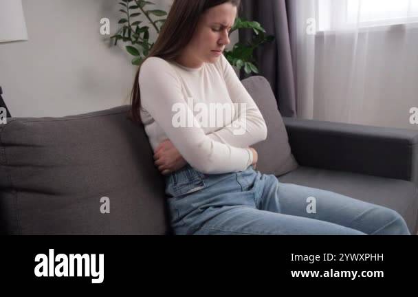Sick young woman in pain holding belly stomach feeling hurt abdomen ache gastritis pancreatitis ...