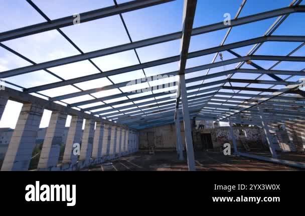 Sun beams go through the frame of the future roof. Man standing on the ...