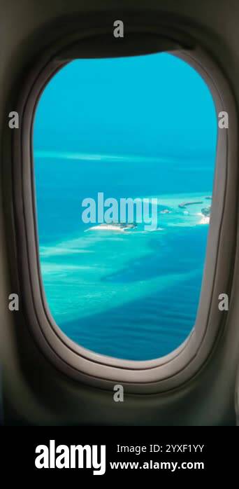 Airplane window shows a beautiful tropical island approaching as the ...