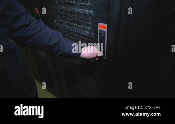 A mans hand opens the server cabinet door. The server is visible. The ...