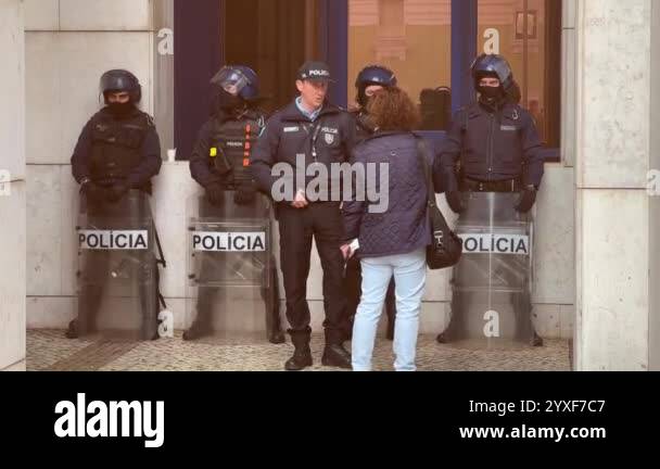 Police officer talking to a woman in front of special forces swat team ...