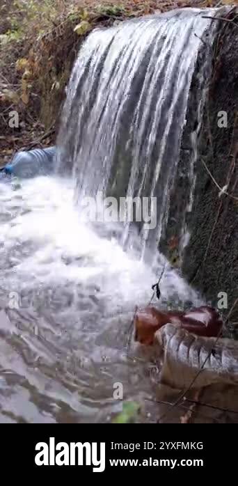 A waterfall in a natural setting polluted with plastic bottles ...