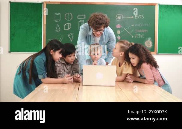 Caucasian teacher and diverse student looking at laptop at classroom ...