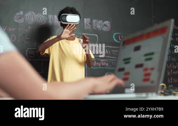 Closeup of school girl hand coding program while african student using VR interact with ...