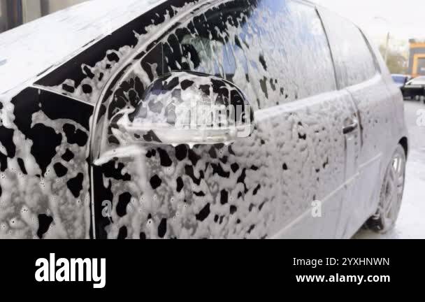 Close-up image of details from a car wash. Black car full of detergent ...