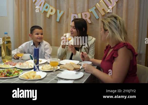 Celebrating a child's birthday, people sit down at the table, drink ...