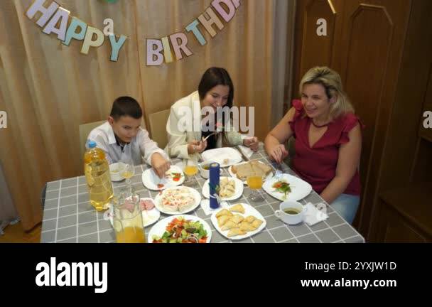 Celebrating a child's birthday, people sit down at the table, drink ...