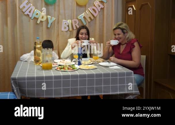 Celebrating a child's birthday, people sit down at the table, drink ...