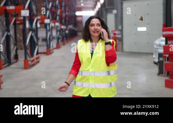 Supervisor woman wearing a safety vest is walking and talking on the ...