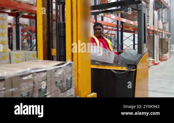 Warehouse worker smiling while driving a forklift in slow motion ...