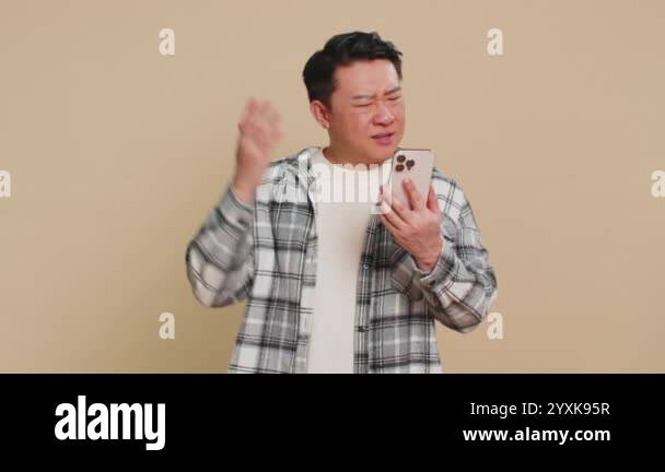 Upset sad Asian man use smartphone typing browsing, play game, loses ...