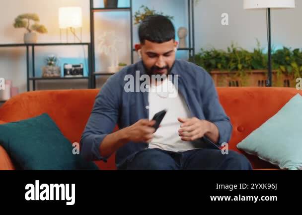 Smiling handsome Indian man taking wireless earphones out of box ...