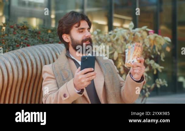 Happy rich Indian businessman tourist using smartphone and counting ...