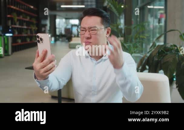 Angry young boss arguing over video call using smartphone while sitting ...