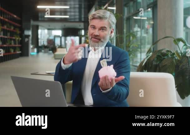 Happy mature businessman entrepreneur save money using pink piggybank ...
