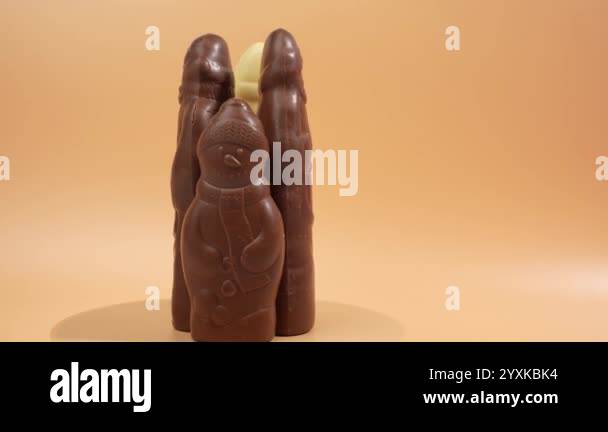 Three chocolate figures of Santa Claus and a snowman rotate on an ...
