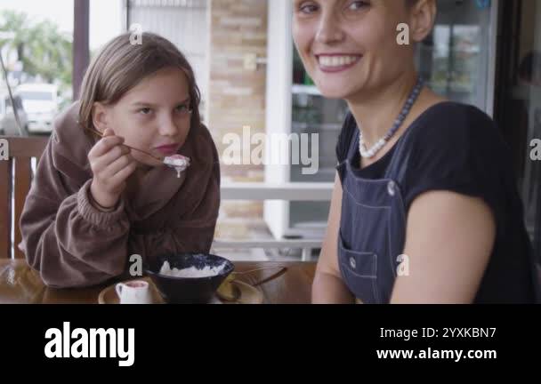 A joyful moment between a mother and her daughter sharing ice cream at ...