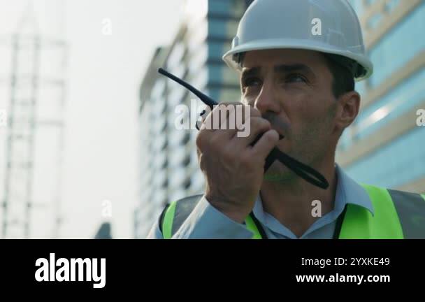 Portrait of man engineer talking with team of workers using radio set ...