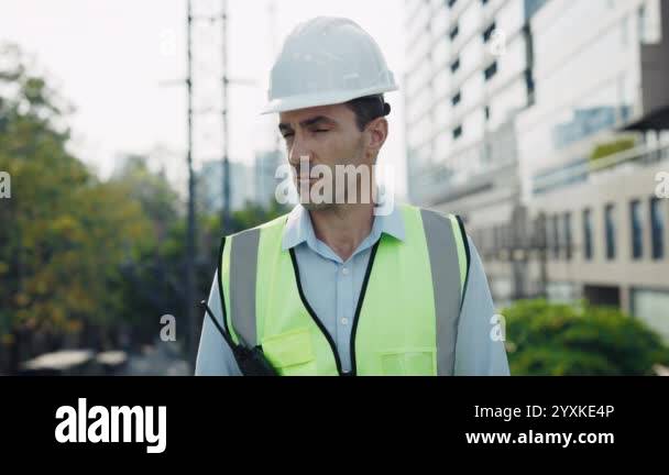 Smiling man engineer with radio set looks at camera. Portrait of male builder in helmet and ...