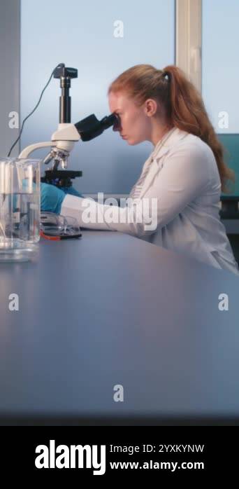 Beautiful female microbiologist in white coat working with microscope ...