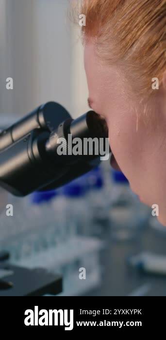 Medical science lab: Close up of female microbiologist looking under ...