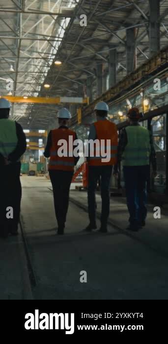Back view of four heavy industry technicians in uniform and helmets ...